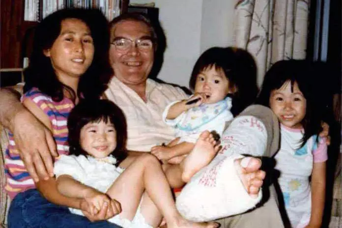 Vecchia foto di famiglia di madre e padre e tre bambini piccoli. Il padre ha una gamba ingessata, ma tutti sorridono.