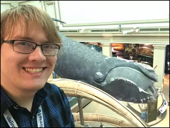 Un visitante sonríe para una selfie junto a la ballena franca del Atlántico Norte en exhibición en el