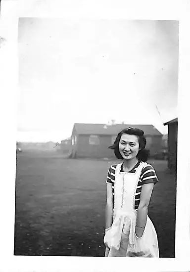 Црно-бела фотографија на млада жена во бел фустан и кошула со пруги