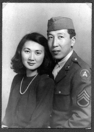 Black and white image of newlywed couple with man in army uniform