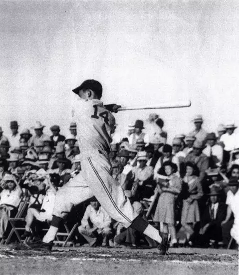 Foto hitam putih Testuo Furukawa mengayunkan tongkat baseball di depan kerumunan kecil