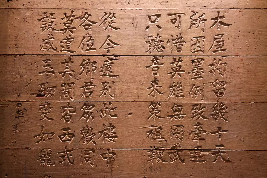 Parede de pedra marrom gravada com caracteres chineses.