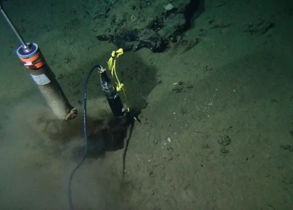 Een troebele groenbruine oceaanbodem met een gereedschap dat in de zeebodem boort