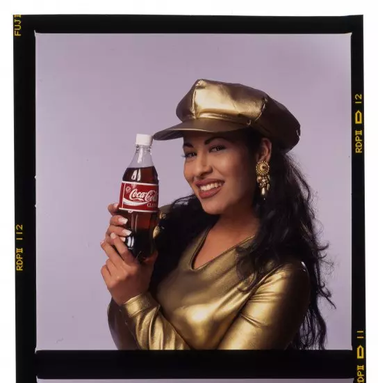 Selena con una gorra dorada sosteniendo una botella de Coca-Cola