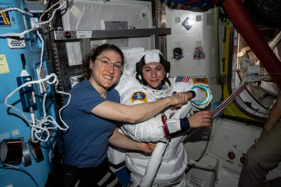 D'Christina Koch (lénks) poséiert fir e Portrait mam Jessica Meir wärend si sech op hiren éischte Spacewalk zesumme virbereeden. (Bild Ugedriwwe vun NASA)