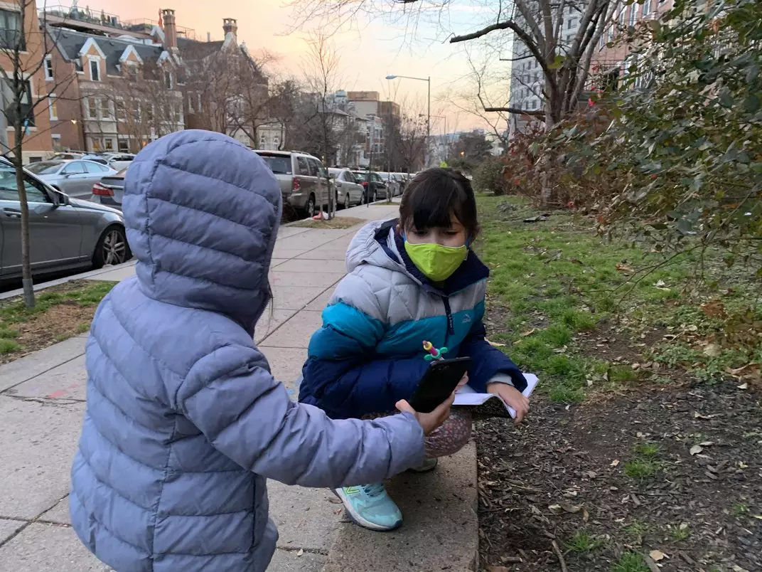 外でノートと携帯電話を使っている2人の子供。