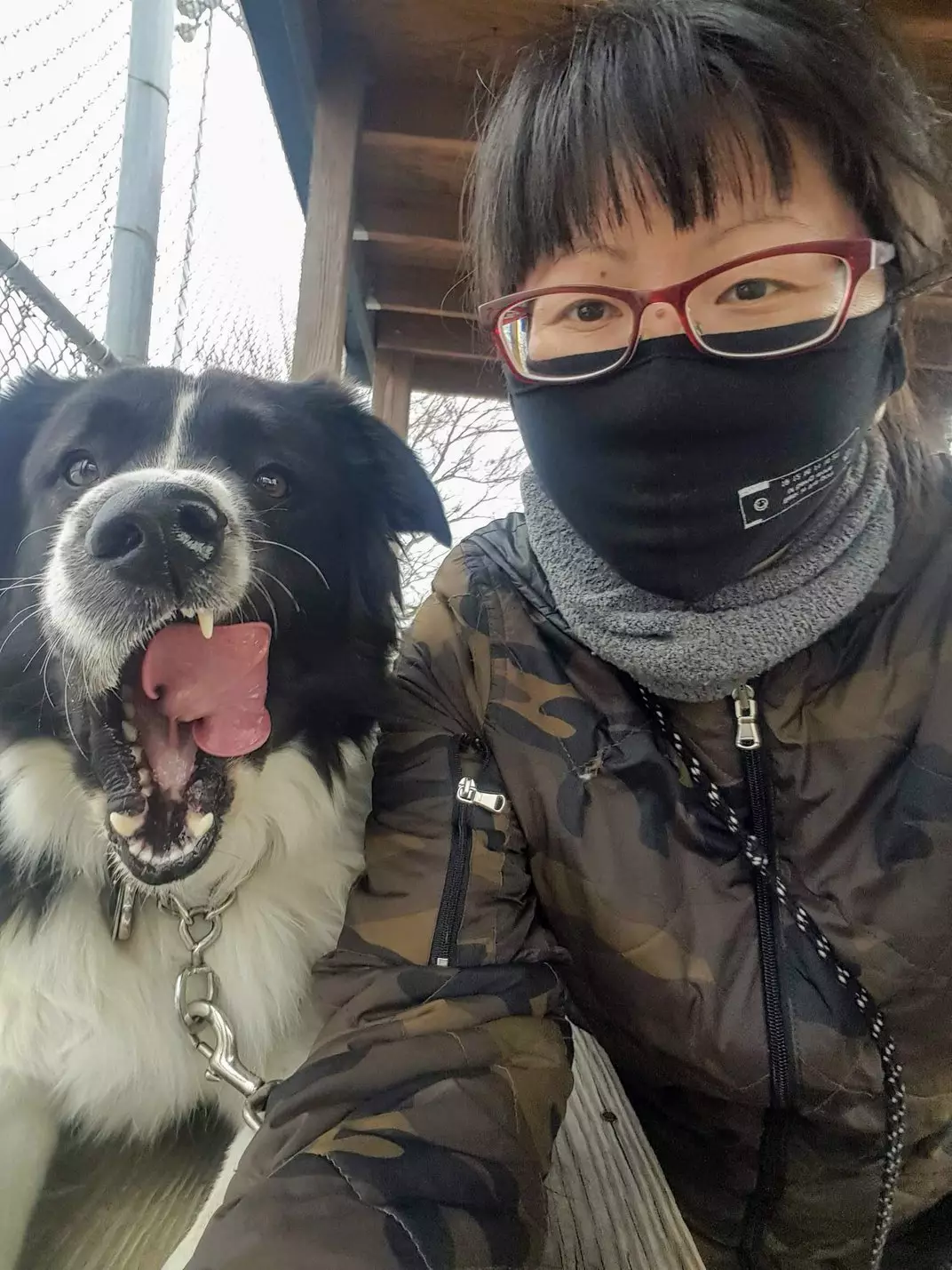 Een gemaskerde persoon naast een hond die zijn kaken likt.