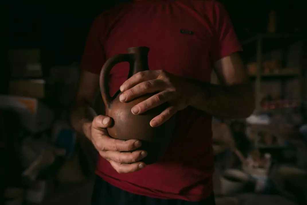 一個黑色的陶罐緊握在一個男人的手中。