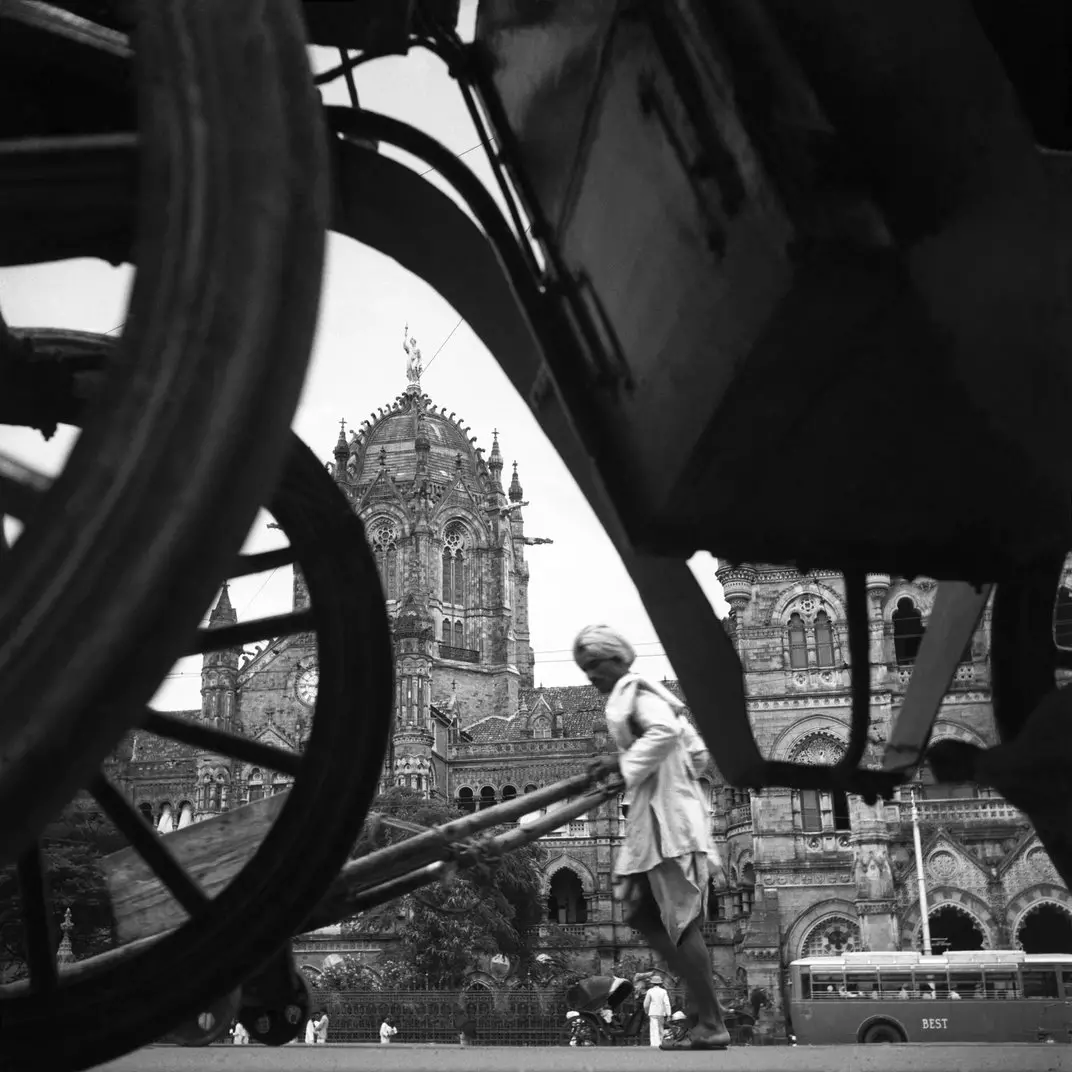 A black and white image of the terminal, a massive colonial structure, as viewed from underneath the wheel of a carriage