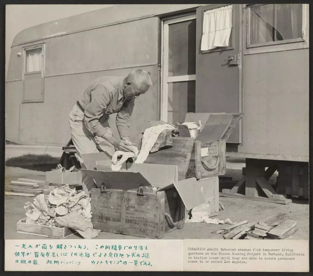 Một bức ảnh đen trắng cho thấy một người đàn ông đang cúi xuống trước một chiếc xe kéo để mở thùng các-tông.