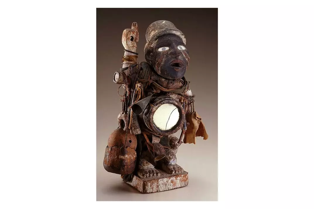 Ceramic or wooden sculpture of a person in a bowler hat, carrying some kind of instrument. Its abdomen appears hollowed out and lit from within.