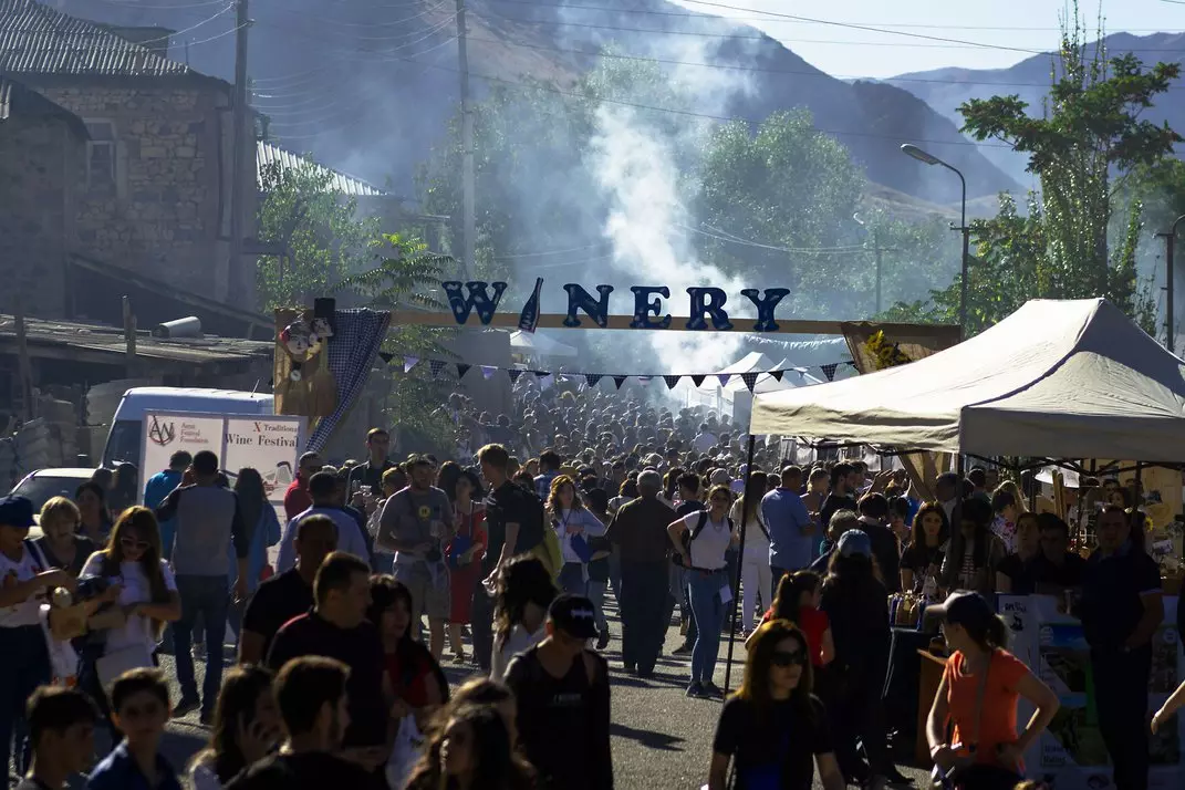 No Festival do Vinho Areni, as pessoas se reúnem em um grande grupo sob uma faixa que lê