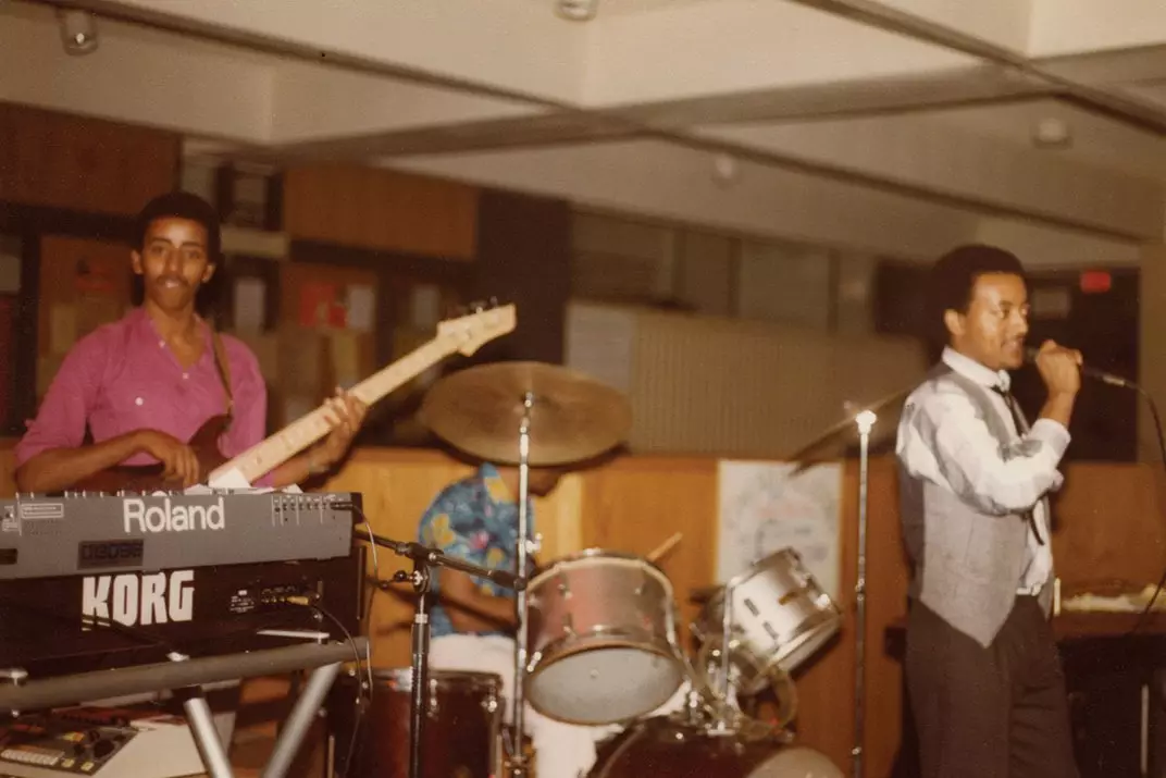 Tatlong miyembro ng banda na gumaganap sa electric bass, drums, at vocals. Larawan ng lumang kulay na pelikula.