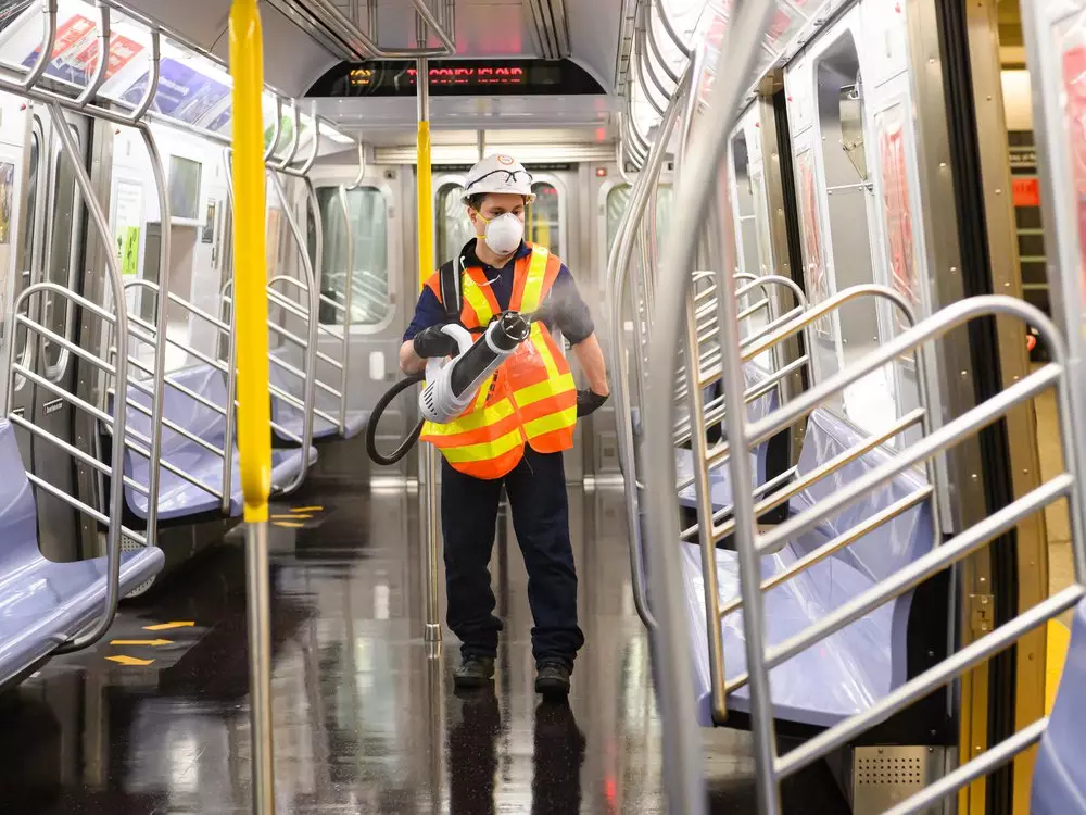 ヘルメット、マスク、安全ベストを着用したMTA労働者は、バルク消毒機を使用してMTA地下鉄車両を徹底的に清掃します