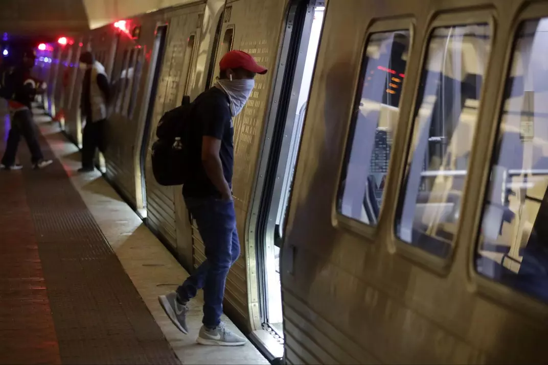 マスクをかぶったメトロライダーがワシントンDCの地下鉄車両に乗り込む。