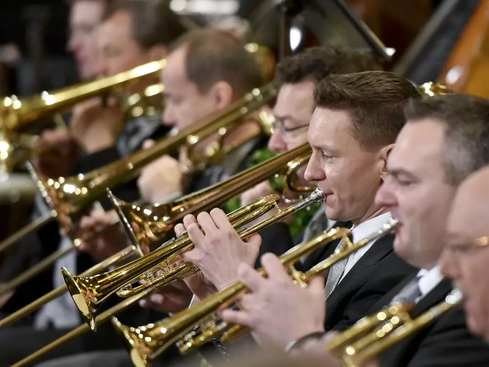 Trumpetister i en orkester sitter på rad under en föreställning