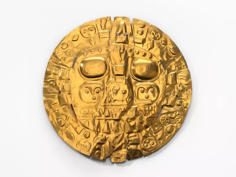 Sobre un fondo branco, un disco dourado brillante con trazos en relieve que representan dous ollos grandes e redondeados, a suxestión dunha especie de rostro e moitos diamantes, círculos, liñas e formas curvas entrelazados.