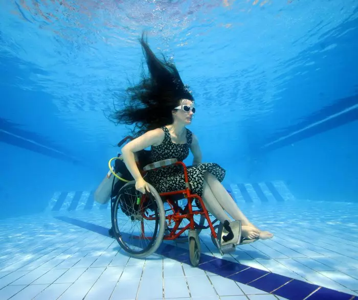 Kunstenaar Sue Austin bekijkt een zwembad in haar onderwaterrolstoel.