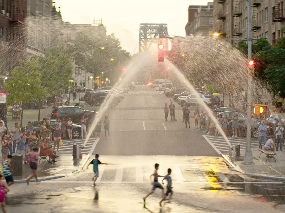 Children run through sprinklers in Washington Heights