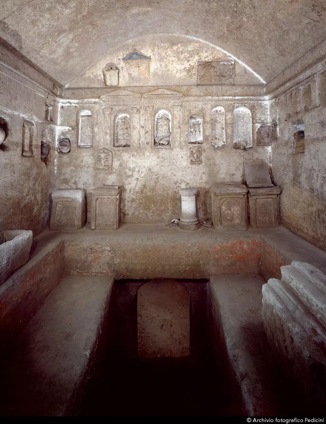 Uitzicht op de bovenste grafkamer, waar grafurnen in nissen boven banken zitten die zijn uitgehouwen voor rouwenden