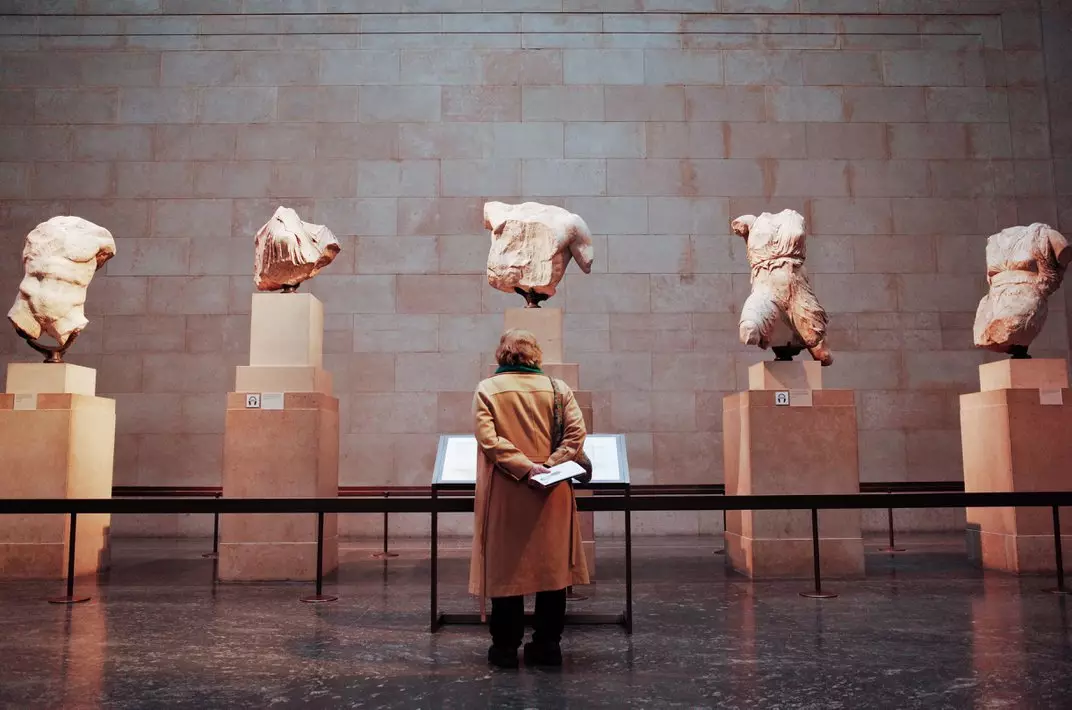 Una donna sta davanti a una selezione di marmi di Elgin in mostra al British Museum