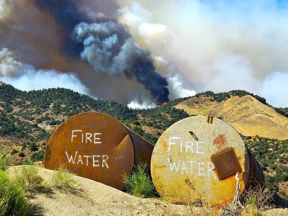 Δεξαμενές γεμάτες με νερό περιμένουν πιθανή χρήση καθώς μια φωτιά καίει στην κορυφή ενός λόφου στο Lebec, Καλιφόρνια, 2010