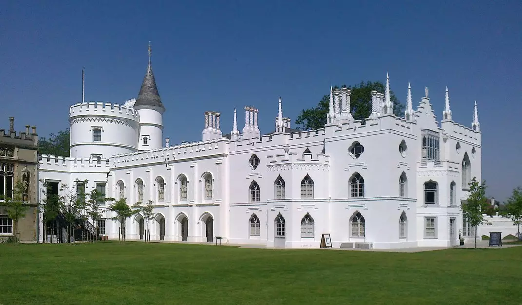 Большой белый особняк, похожий на замок, с круглыми башнями и шпилями, весь ярко-белый на фоне голубого неба и зеленой травы.