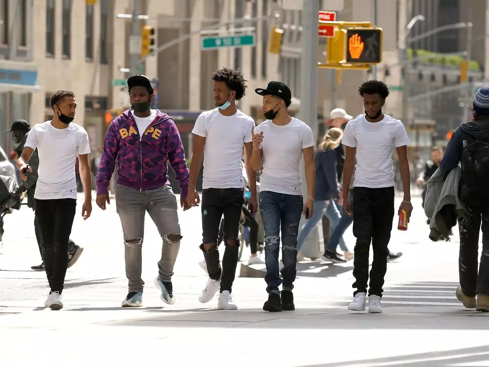 保護マスクを着用した男性のグループが、2021年4月10日にニューヨーク市のミッドタウンを歩きます。