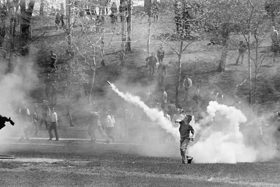 Un estudiante de la Universidad Estatal de Kent lanza un bote de gas lacrimógeno hacia los miembros de la Guardia Nacional.