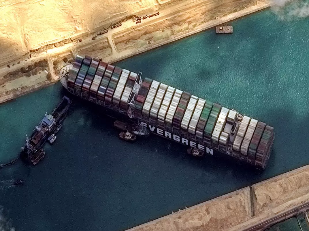 Laevalaev Ever Given on kujutatud külili kiilutuna, blokeerides Suessi kanali