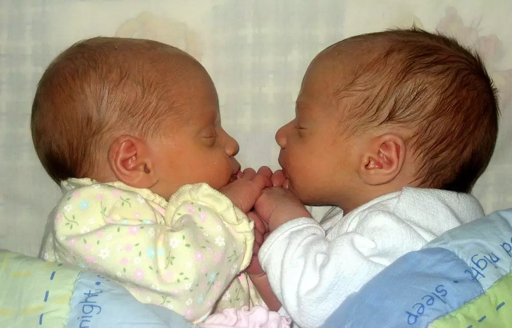Et bilde av to nyfødte som står overfor hverandre og holder hender