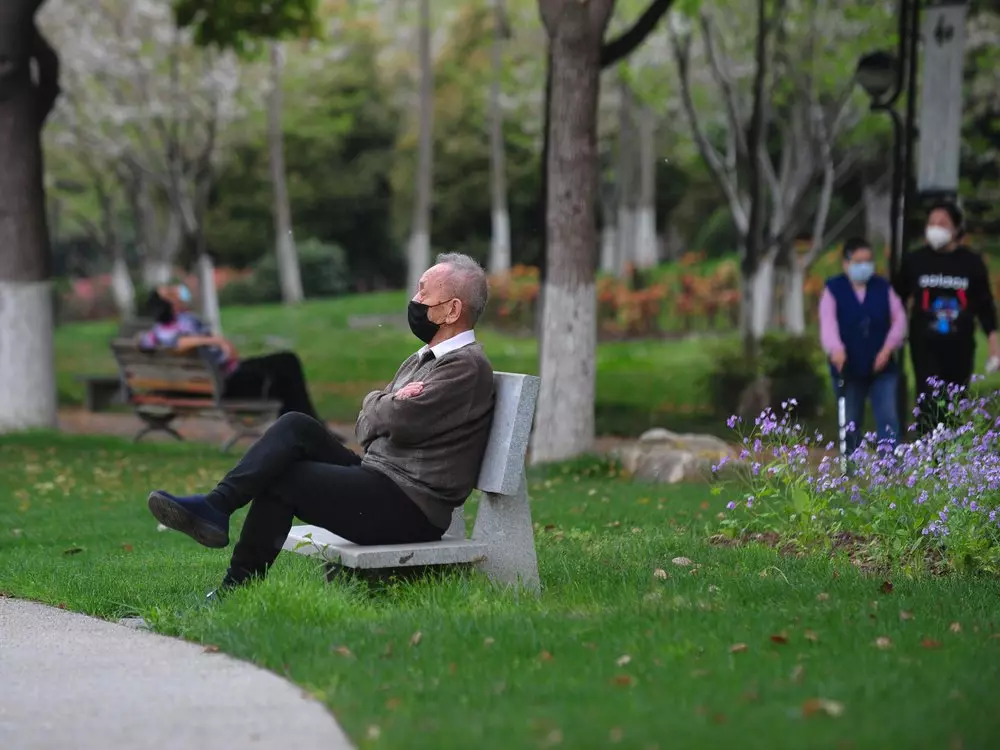 Starszy mężczyzna odpoczywa na ławce po ponownym otwarciu parków w Wuhan w czwartek
