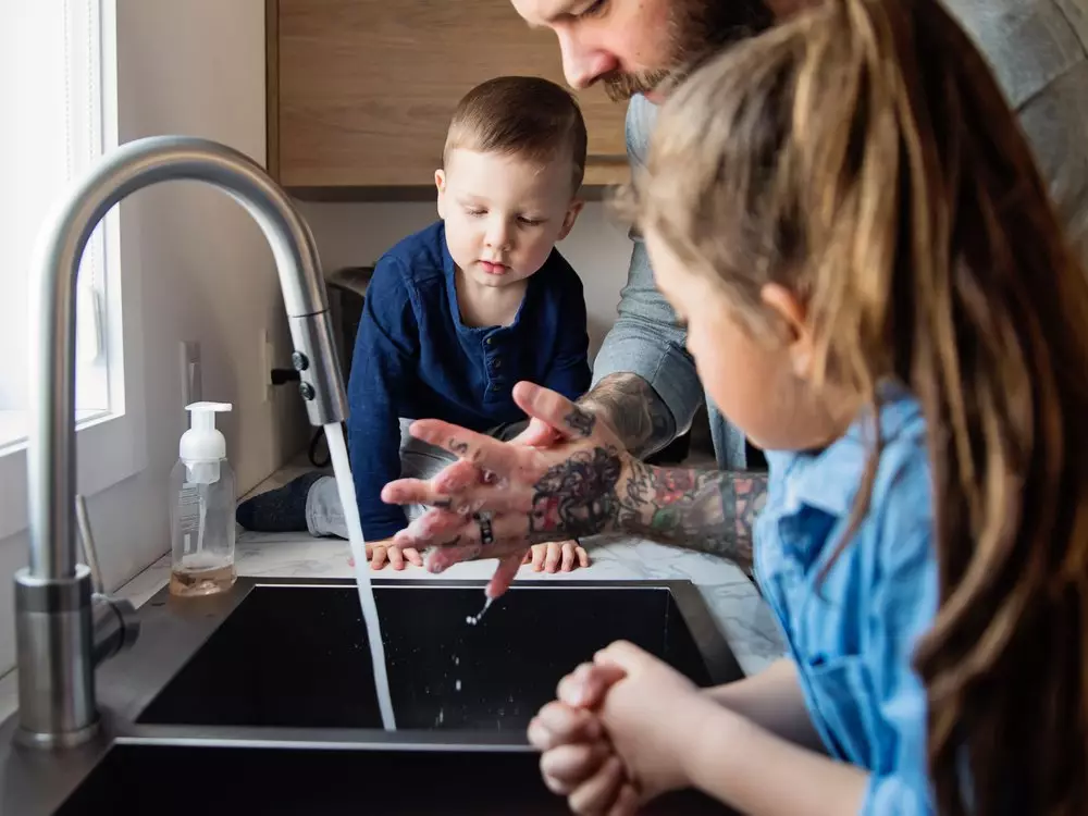 батько вчить дітей, як мити руки