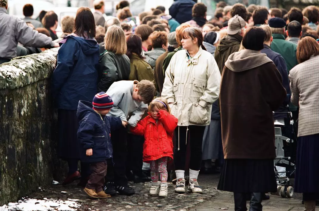 Bambini e adulti si riuniscono fuori dalla Dunblane Primary School poco dopo la sparatoria