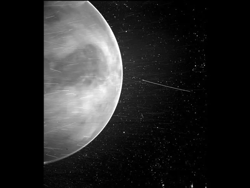 NASAの新しい金星が中央に垂直に配置されたレターボックス画像。惑星の半分は画像の左側に配置されており、天体がズームしていて、背景に星があります。