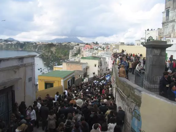 Toeschouwers volgen de processie door het vissersdorpje Corricella.