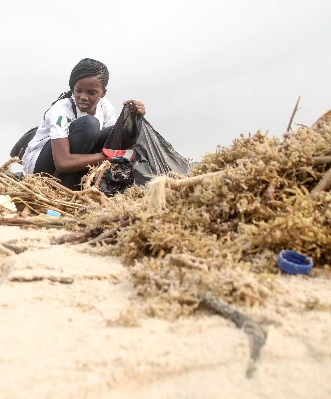 dívka uklízí plastové odpadky na pláži