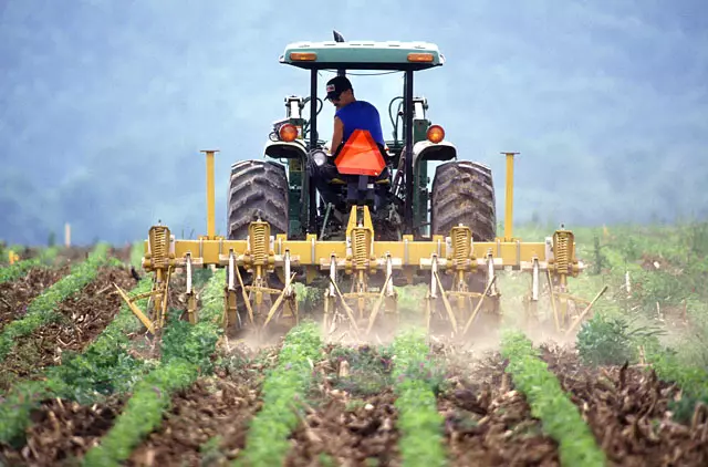 Person på en traktor som bearbetar jordbruksmark