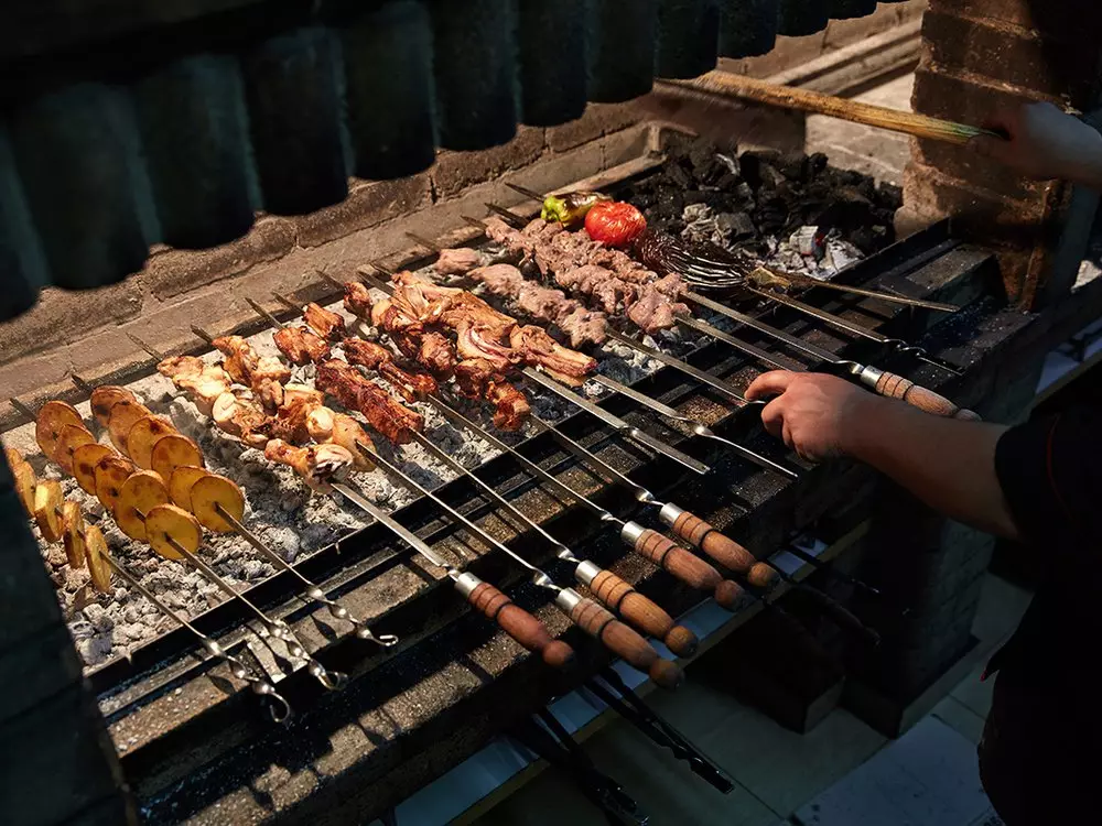 Kuchař pracuje na špejlích khorovats v restauraci Taron v Jerevanu.