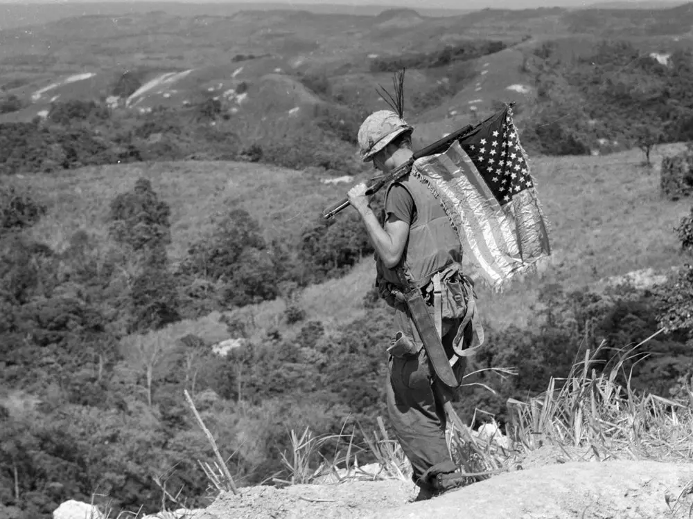 ASV jūras kājnieks atkopšanas operācijas laikā uz savas šautenes nēsā Amerikas karogu