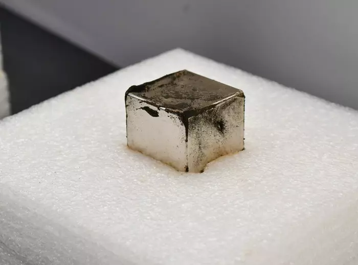 Een afbeelding van meteorietstof dat tegen een kubusvormige magneet rust