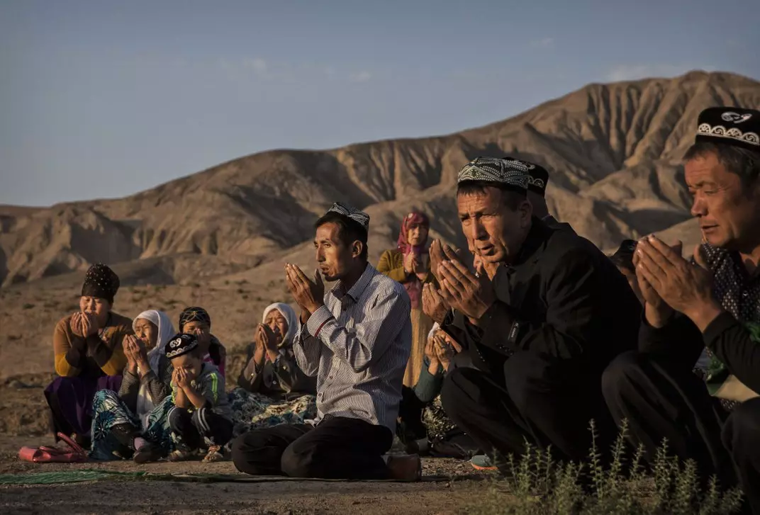 新疆ウイグル自治区のウイグル人家族は、2016年9月12日、コーバンフェスティバルの朝に愛する人の墓で祈っています。