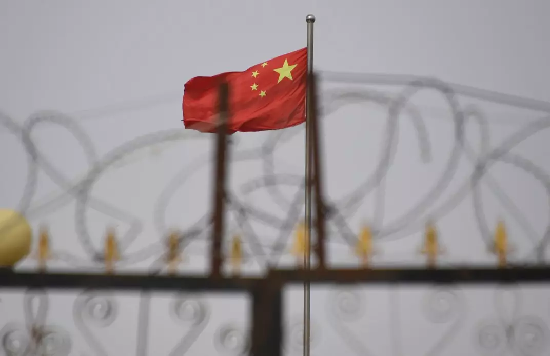 Фотографија на 4 јуни 2019 година на кинеско знаме зад жилет во станбена комплекс во Јангисар, во западниот кинески регион Ксинџијанг.
