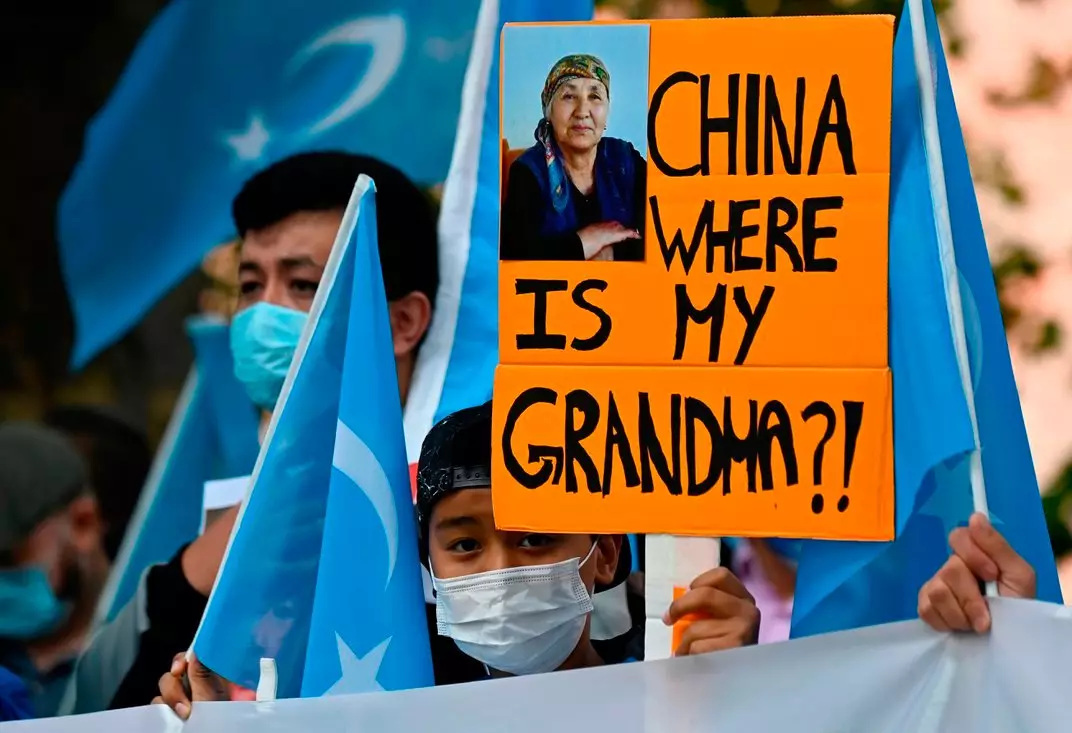 ناشط شاب من الأويغور يحمل ملصقًا مكتوبًا عليه