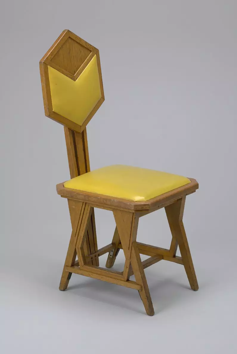 Una sedia laterale in rovere con cuscini in similpelle gialla sul sedile e sullo schienale quadrati