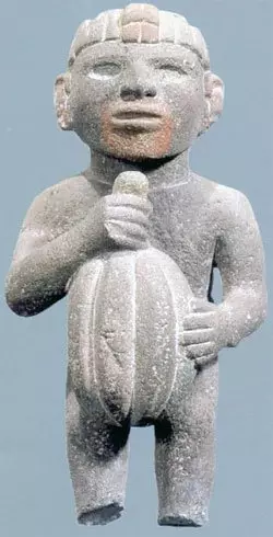 Una figurilla azteca sostiene una vaina de cacao