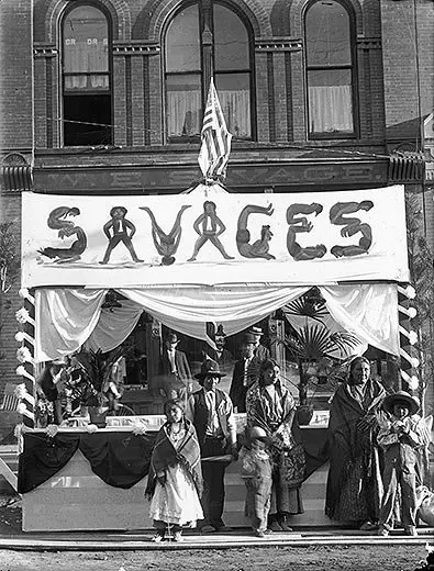 美洲印第安人在一個攤位前擺姿勢，標有 SAVAGES 廣告