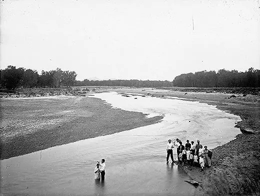 Home batejant dona en un riu amb gent mirant