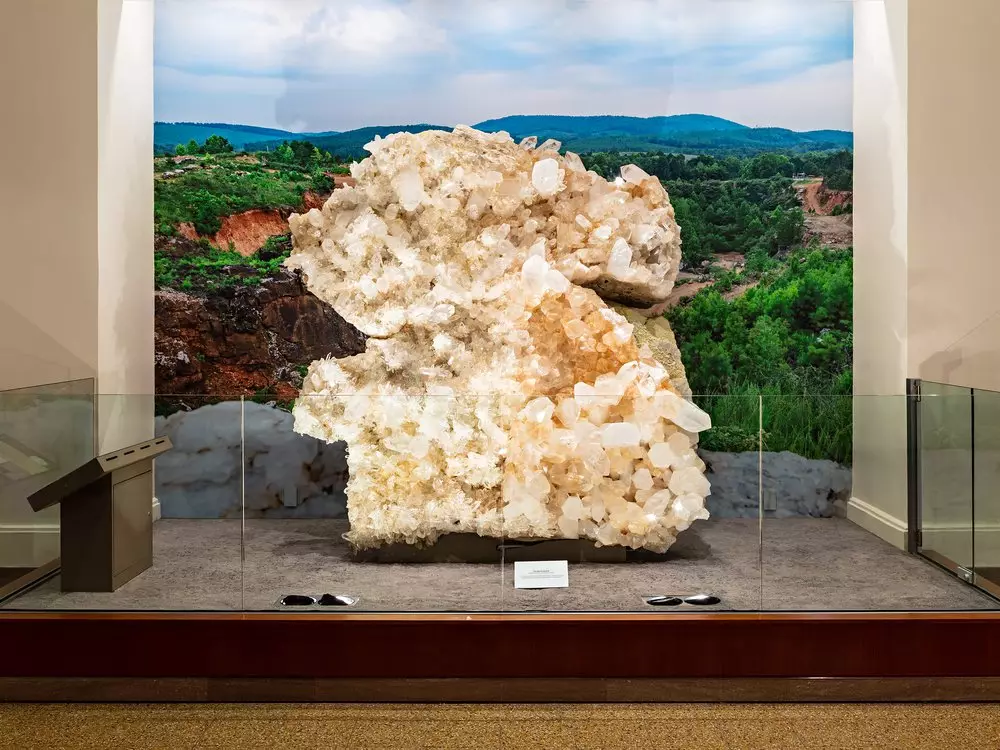 תצוגת מוזיאון של קוורץ ברנס מהחזית. הדגימה נמצאת מאחורי זכוכית בגובה נגדי עם רקע של הרי אואצ'יטה של ארקנסו.