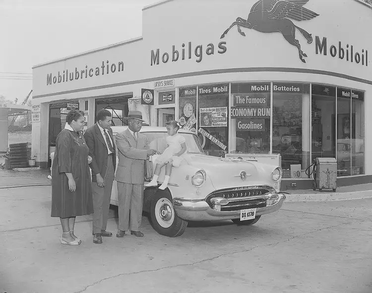 Prodajalec avtomobilov in družina stojita pred bencinsko črpalko